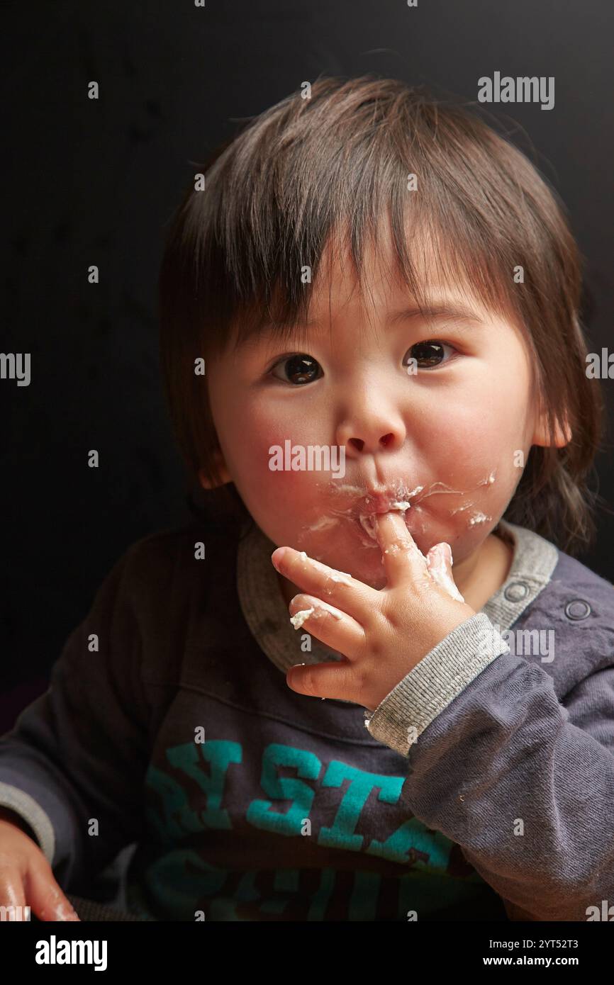 Boy sucking finger with cream Stock Photo - Alamy