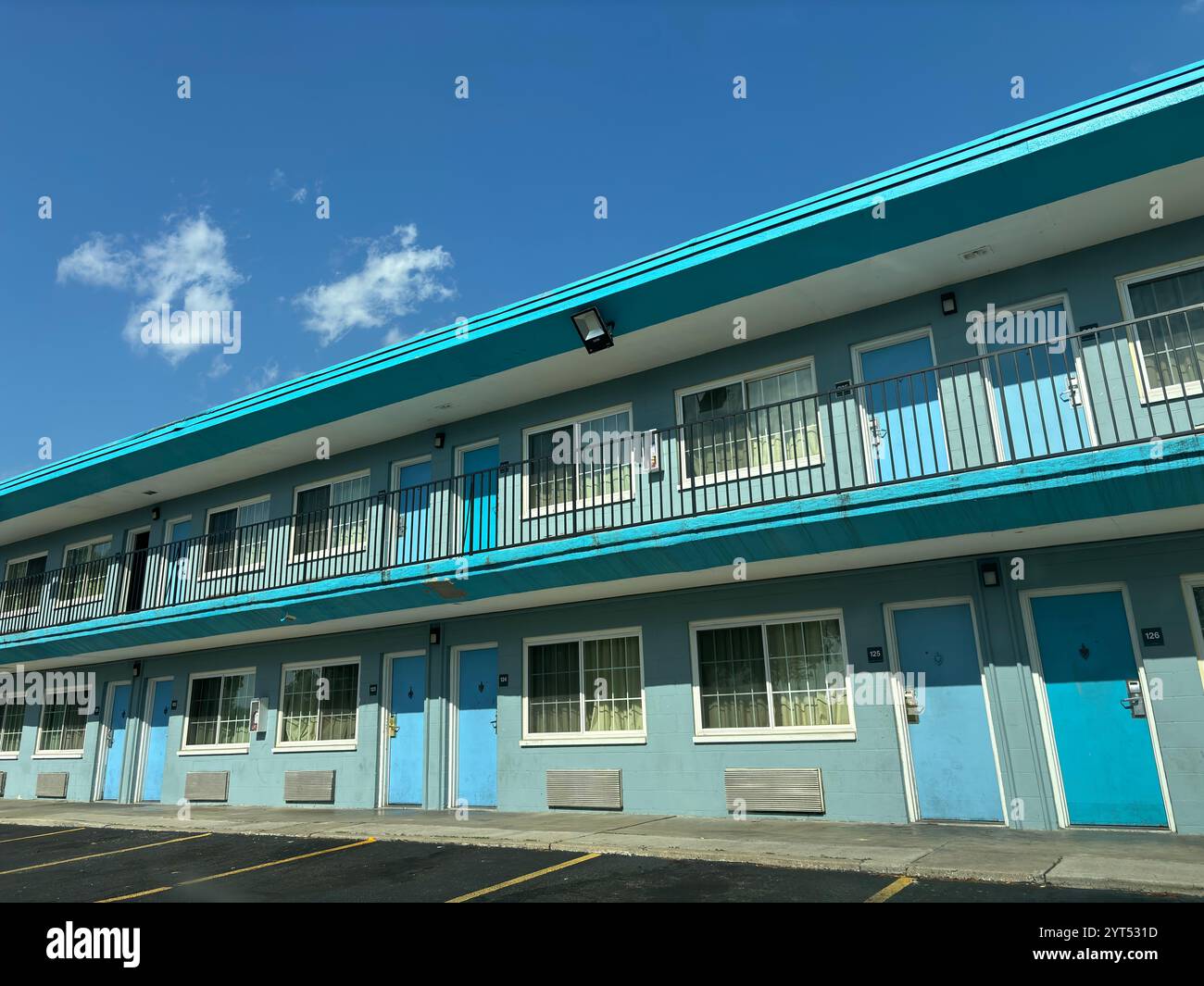 Abandoned two-story retro blue motel exterior under blue sky Stock ...