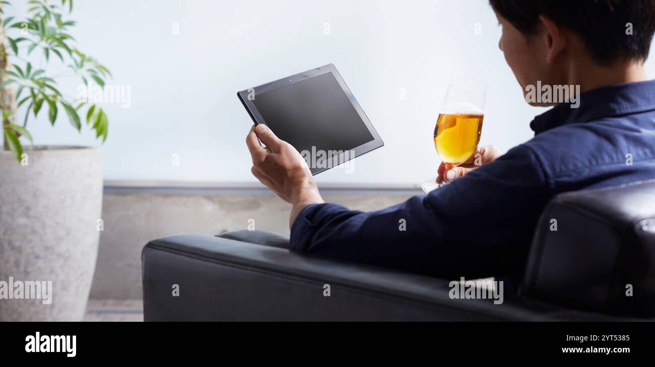 Man operating tablet device while drinking beer Stock Photo - Alamy