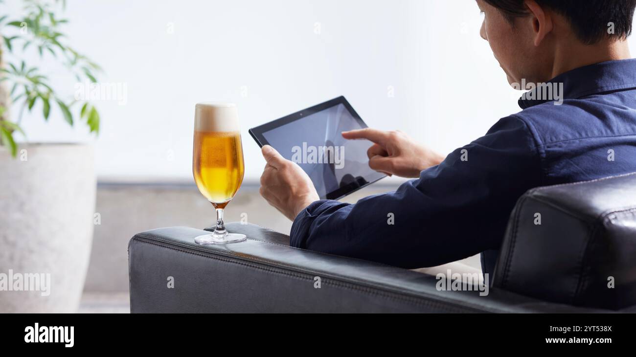 Man operating tablet device while drinking beer Stock Photo - Alamy