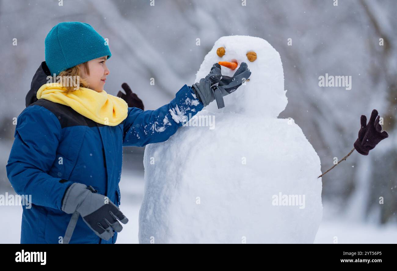 Winter child play with snowman in winter. Snowman with a carrot nose on ...
