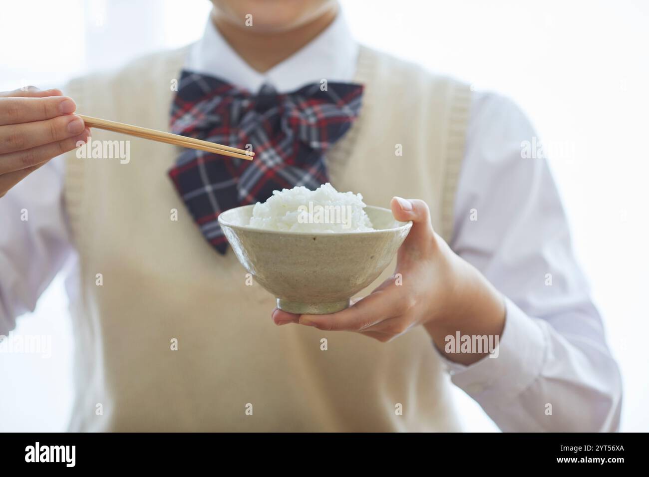 Female student holding a tea bowl and eating rice Stock Photo - Alamy