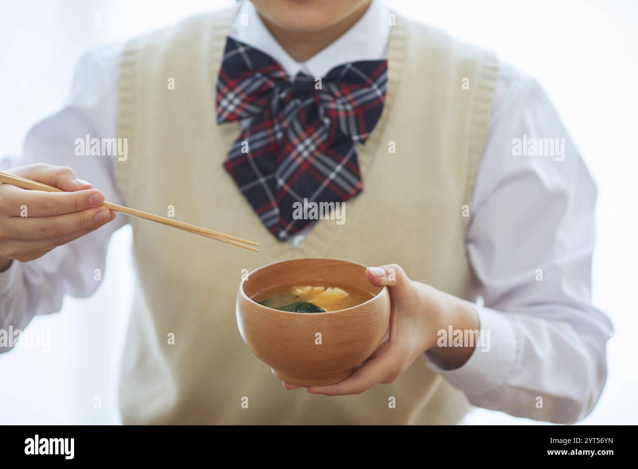 Female student holding bowl and eating miso soup Stock Photo - Alamy