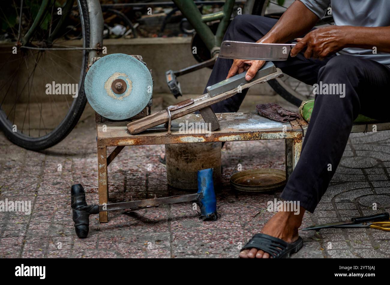 A man sharpening knives by hand in the streets of Saigon in Vietnam ...
