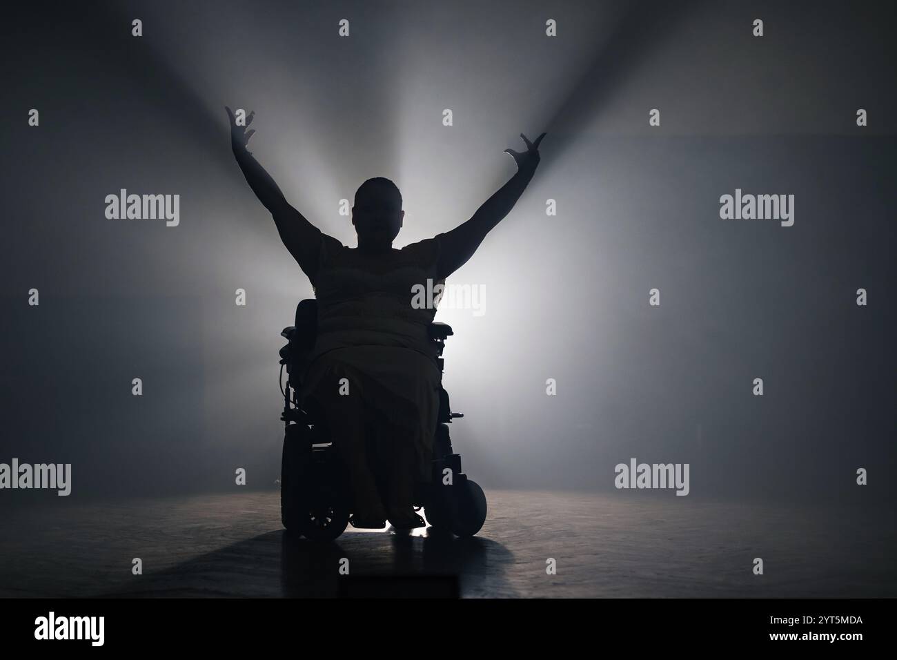Female silhouette, para dancer on wheelchair in a dark space with stage ...