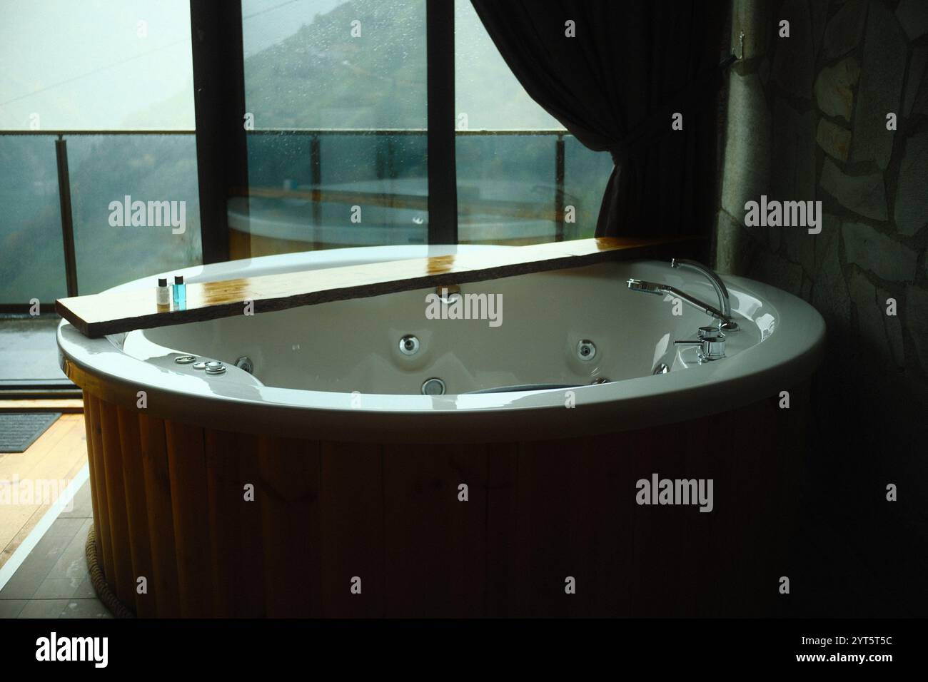 A round jacuzzi with a view of the terrace and mountains from a large ...