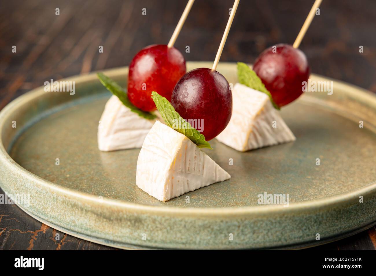 The snack consists of pieces of brie cheese and grapes on toothpicks ...
