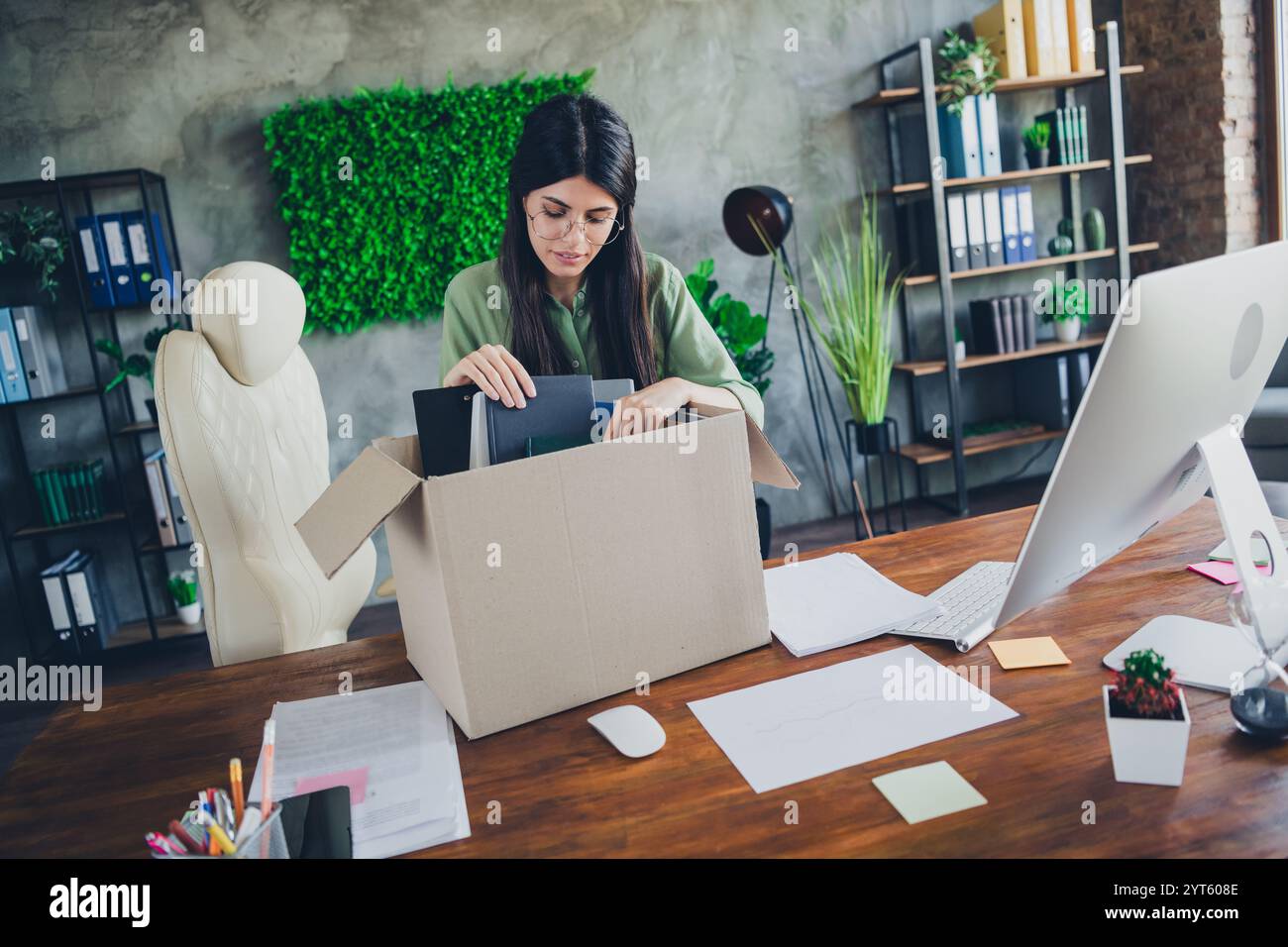 Young professional woman preparing her office desk, organizing ...