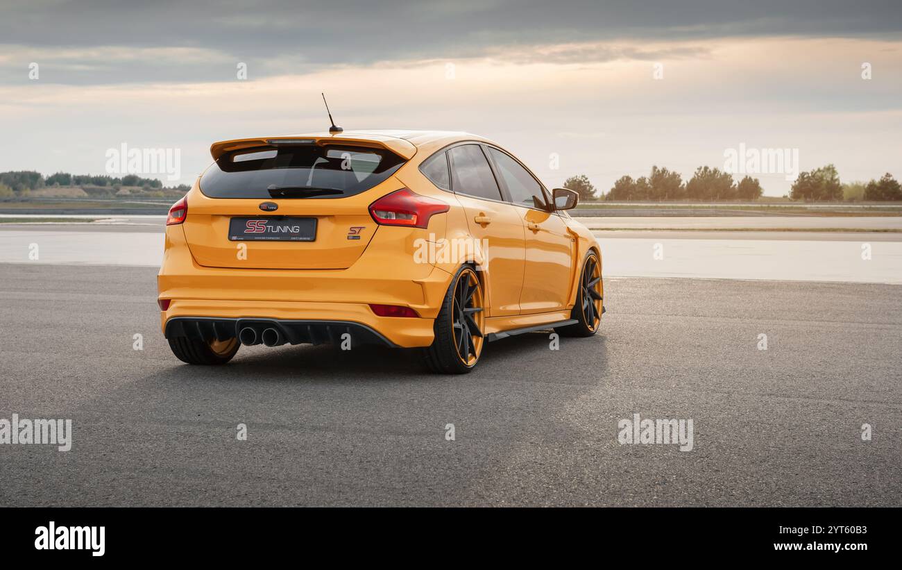 Yolk yellow Ford Focus ST on a racetrack. Three quarter rear view of ...