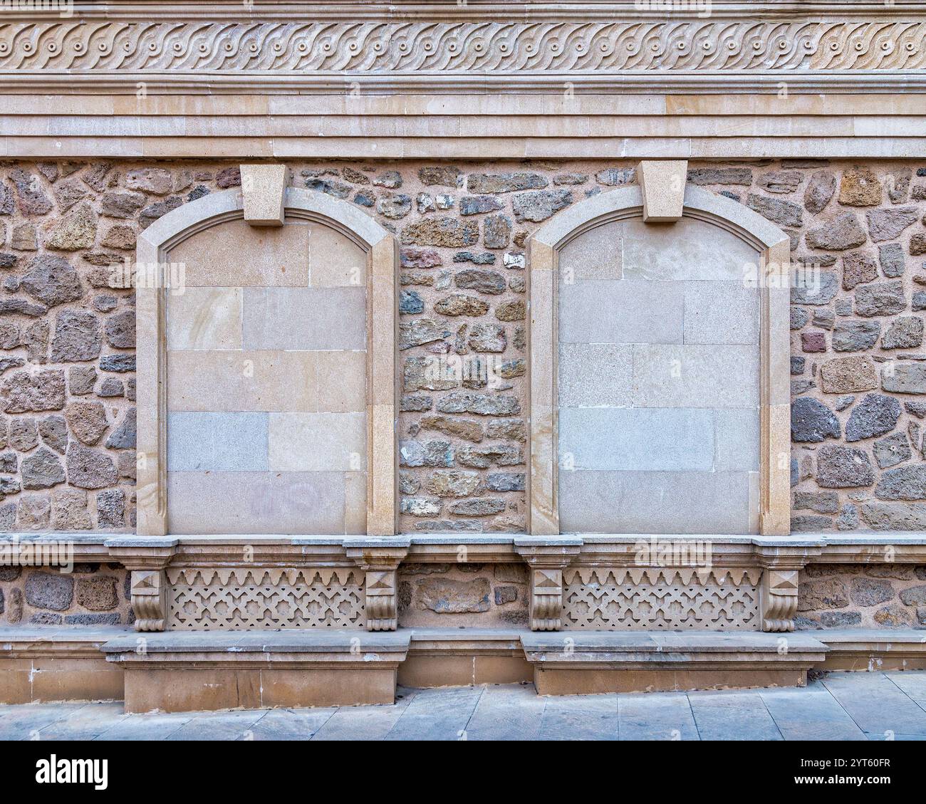 Rustic stone wall showcases decorative niches with intricate carvings ...