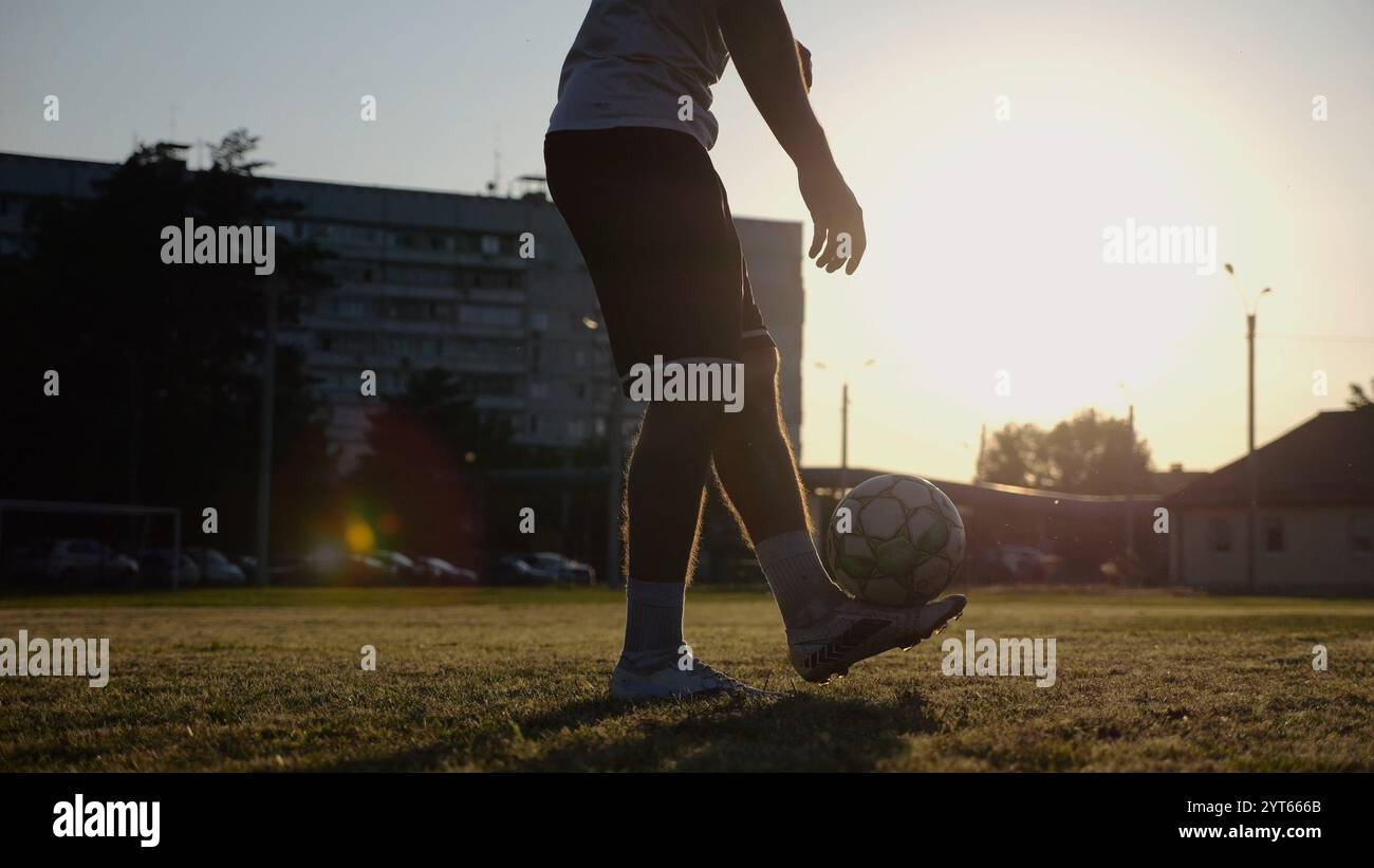 Legs of young man kicking ball at green field. Male feet of ...