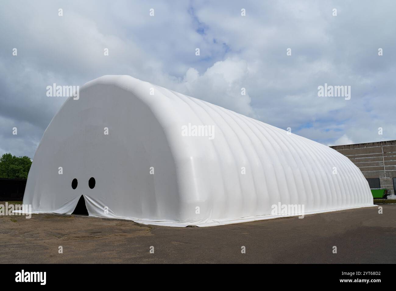 A strikingly large inflatable structure sits on a paved area ...