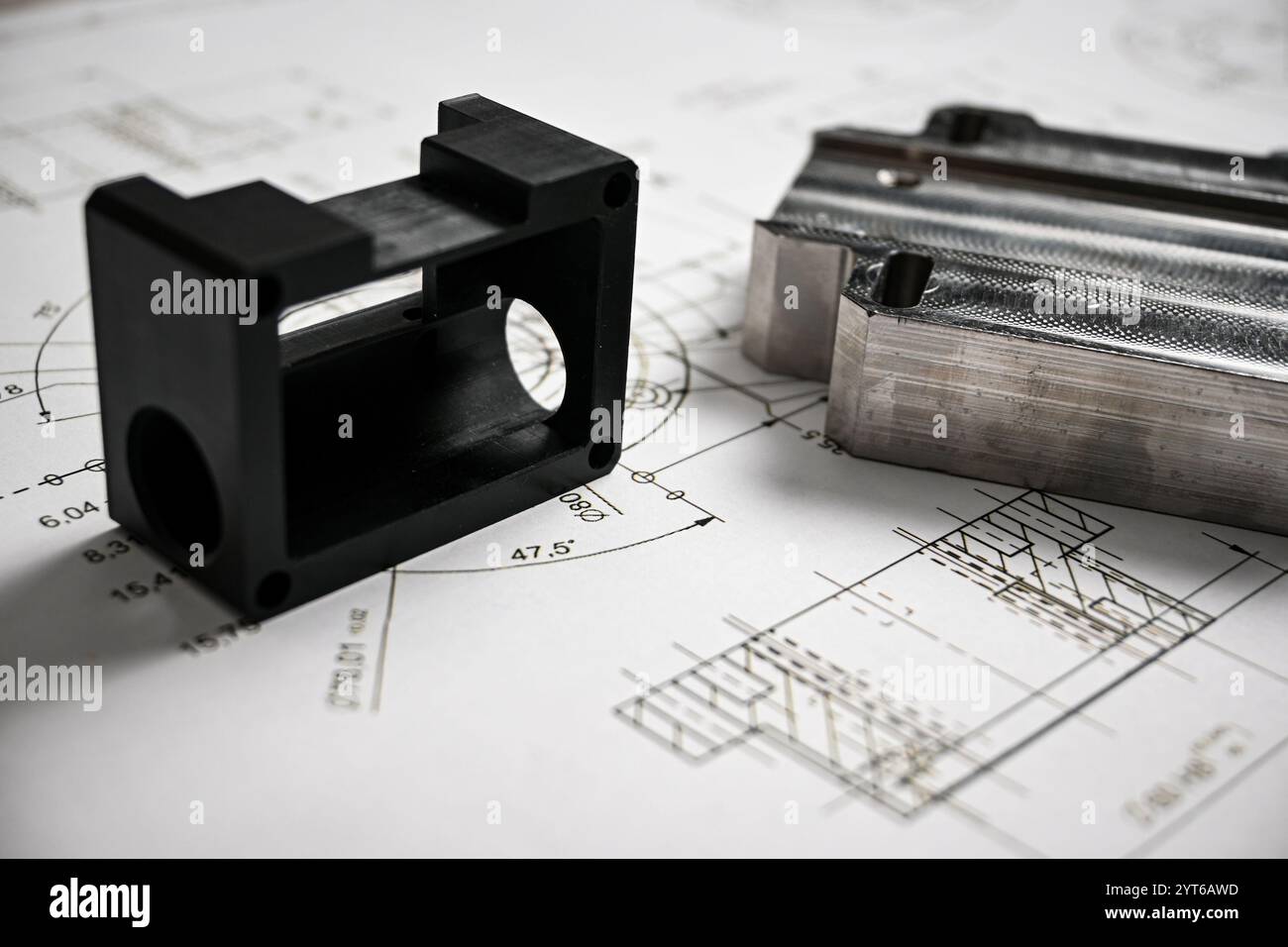 Plastic and metal prototypes are lying on a technical drawing with ...