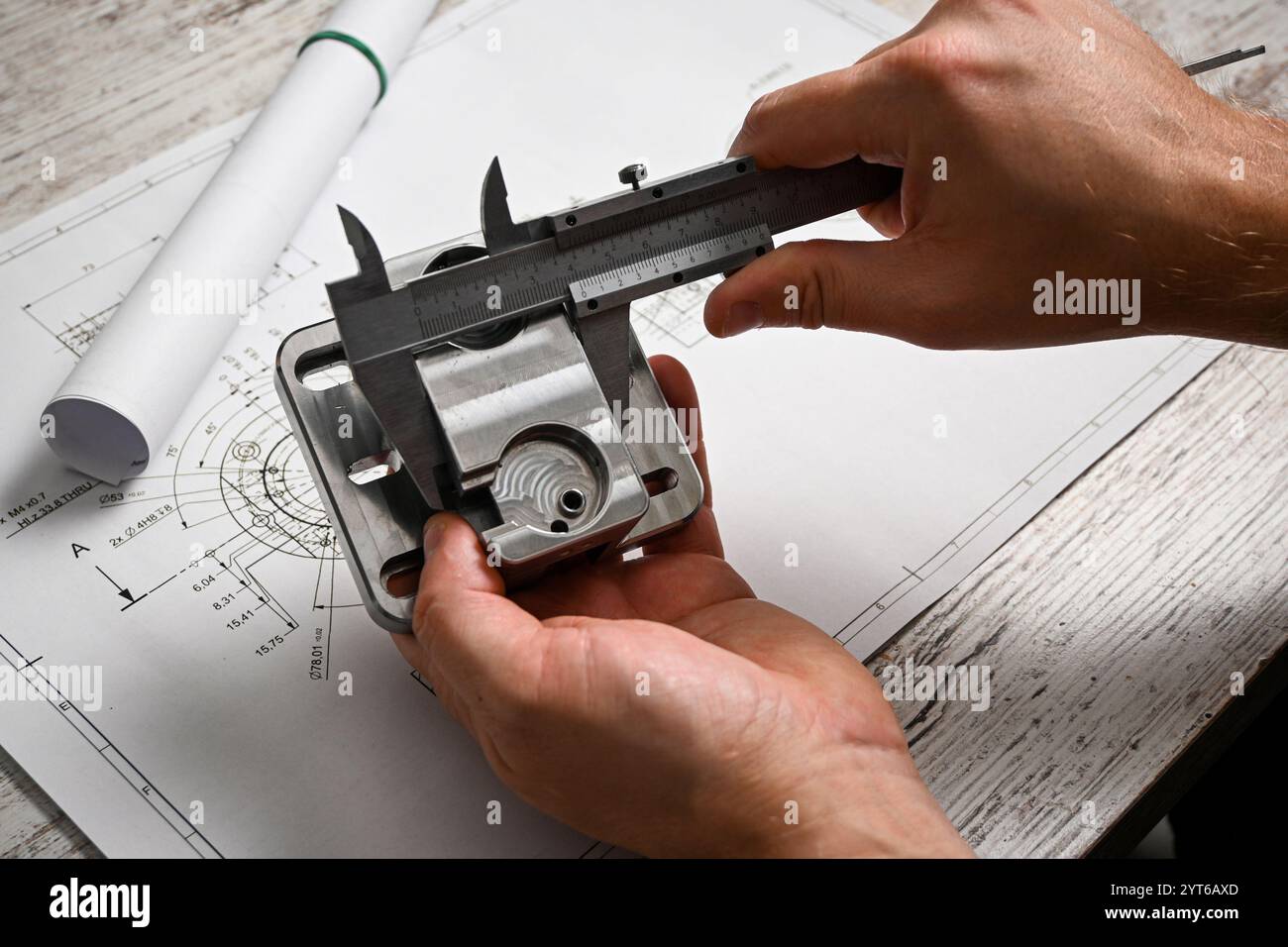 Engineer using caliper to measure a machined part comparing it with its technical drawing Stock ...