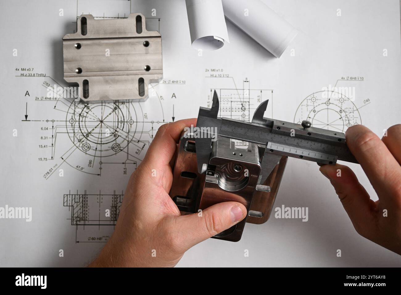Engineer using caliper to measure a machined part comparing it with its ...