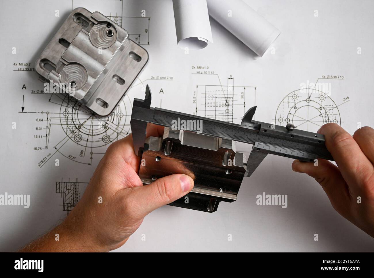 Engineer using caliper to measure a machined part comparing it with its ...