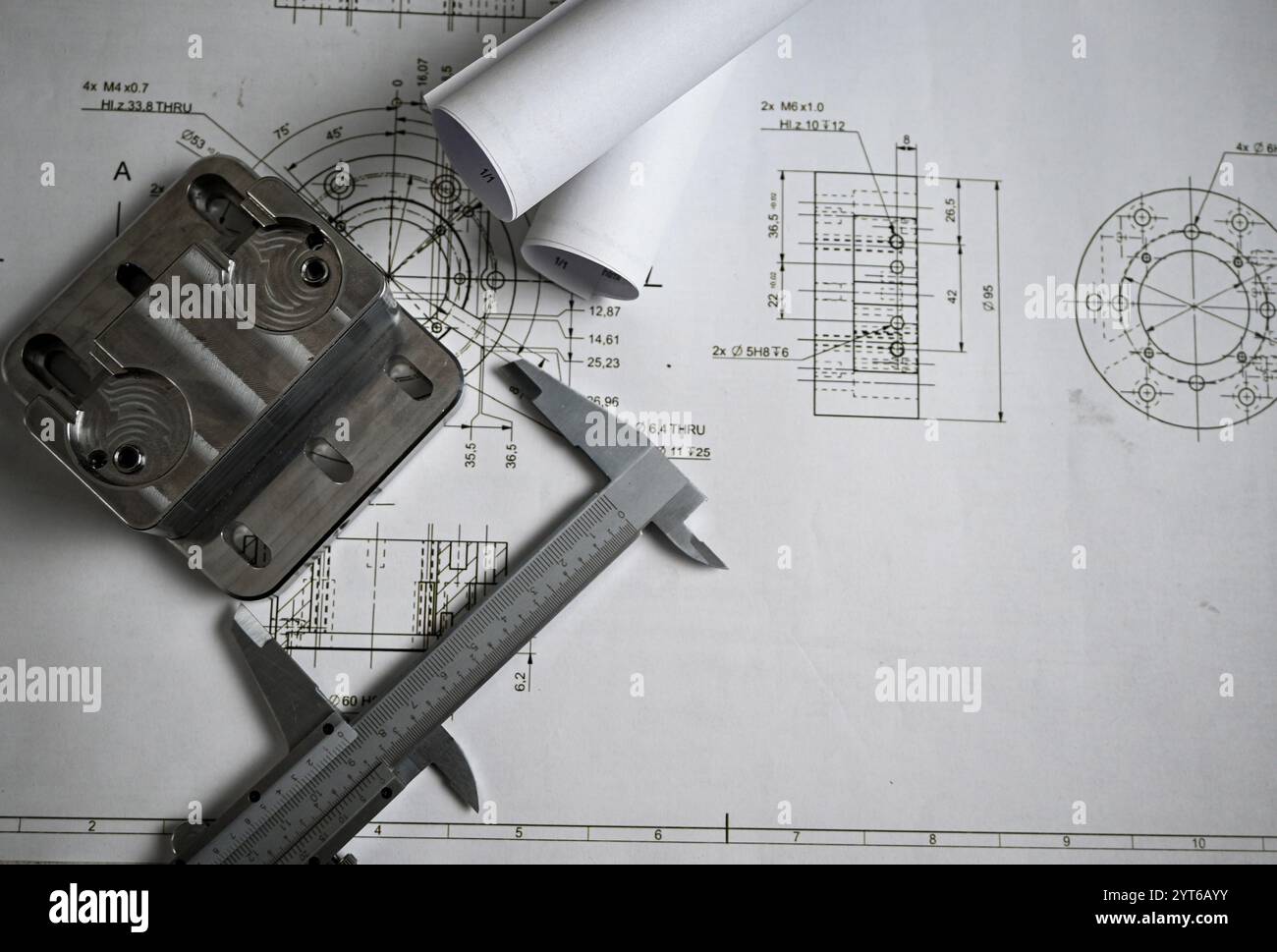 Metal machined part being measured with a caliper, placed on top of ...