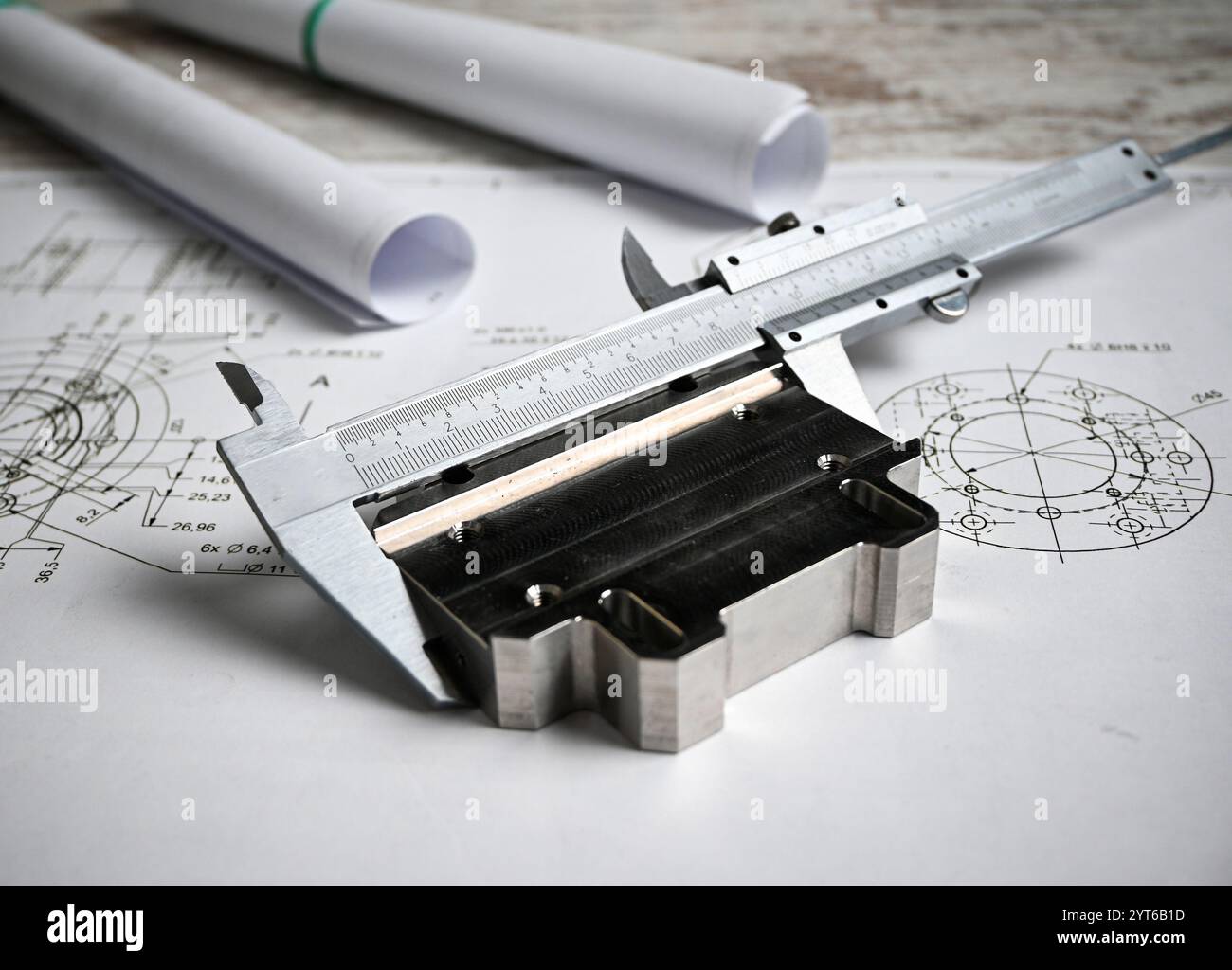 Metal machined part being measured with a caliper, placed on top of ...