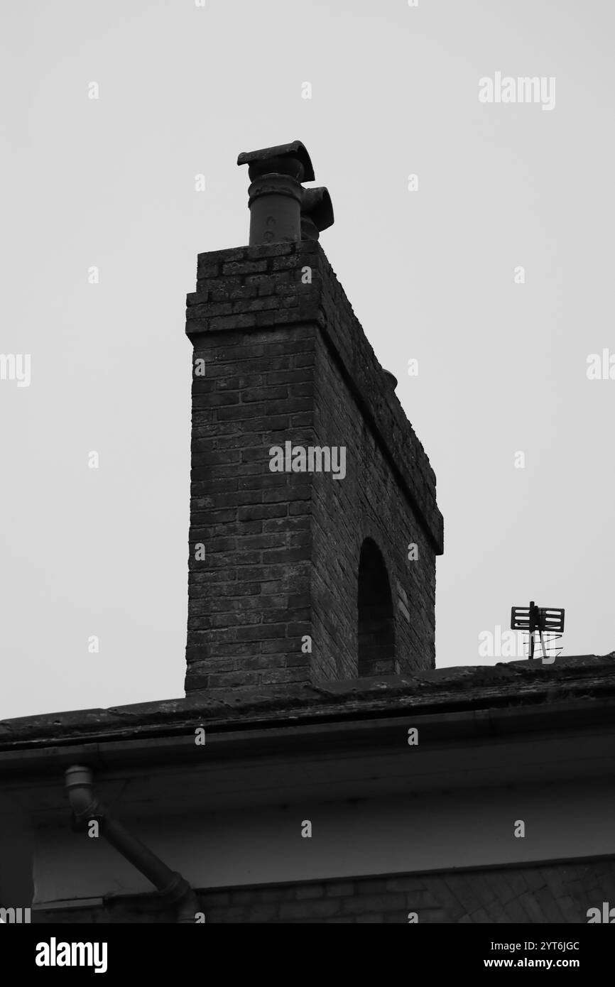 Grayscale, monochrome view of a tall chimney with flues and an opening ...