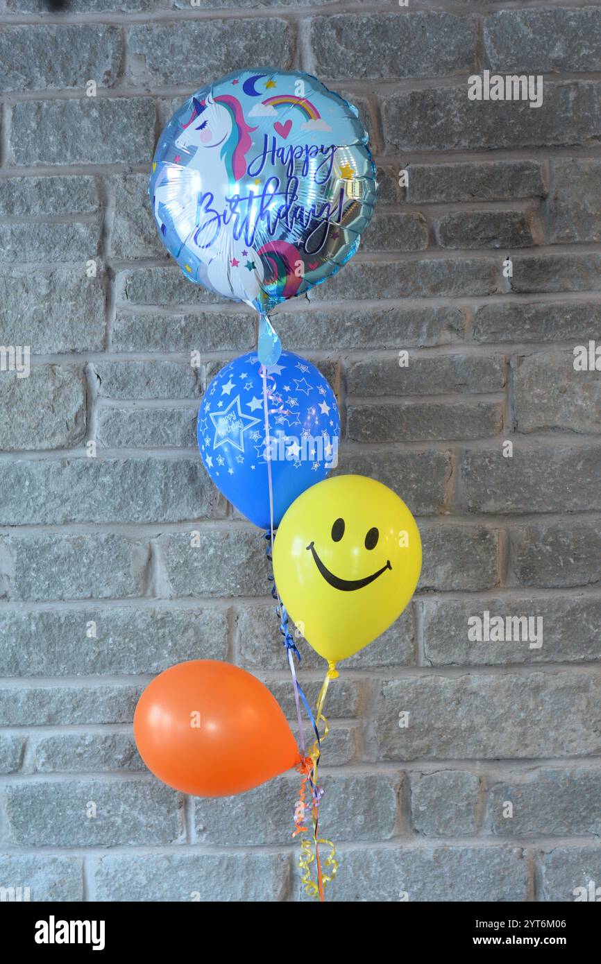Four colorful helium happy birthday balloons float on a string in front ...