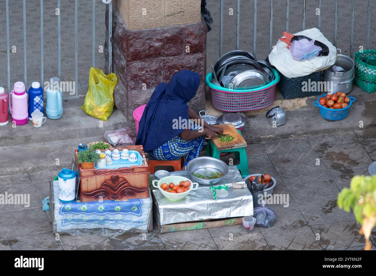 A woman cuts up vegetables and prepares food on the street in Dire Dawa ...
