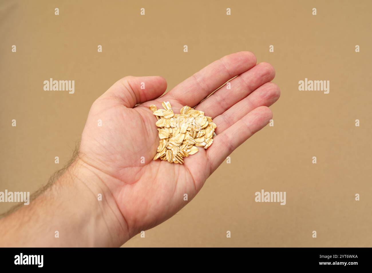 Close-up of caucasian male hand holding rolled oats in palm of hand ...