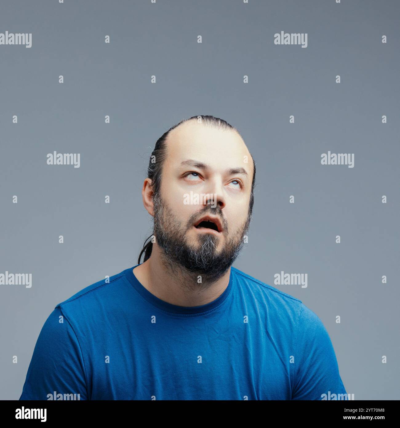 Frustrated young man rolling his eyes and glancing upwards, showcasing ...