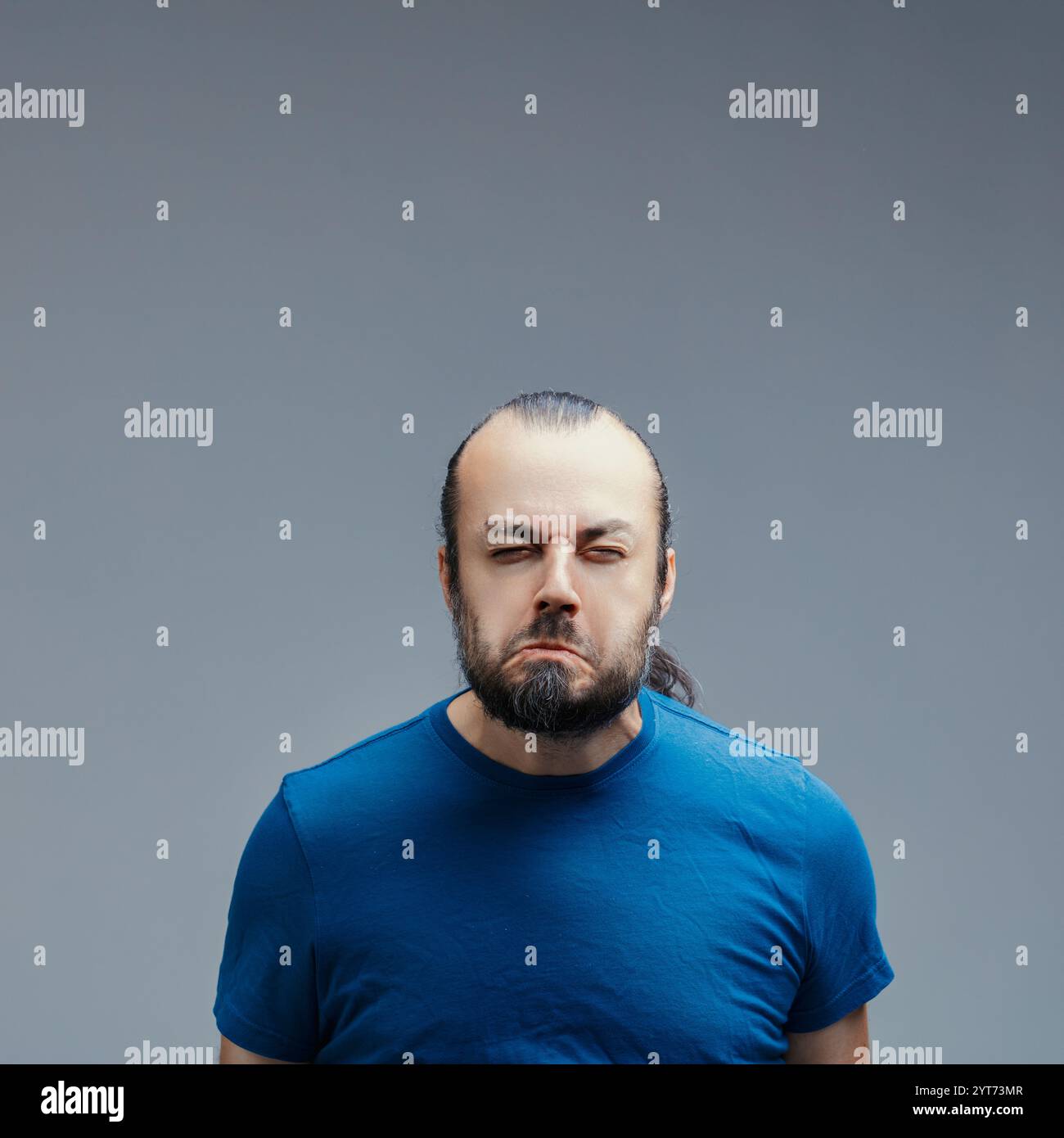 Mid adult man with a beard and long hair in a ponytail, wearing a blue ...