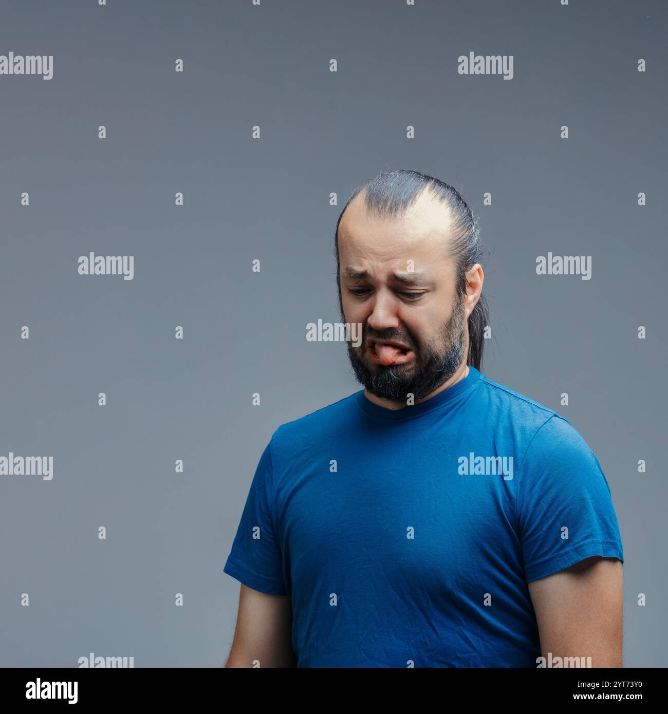 Mid adult man with a beard and ponytail, wearing a blue t-shirt ...