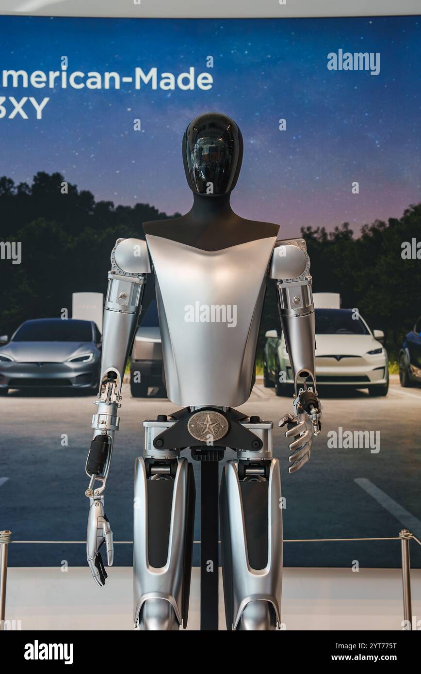 A humanoid robot with a sleek metallic design stands before electric ...
