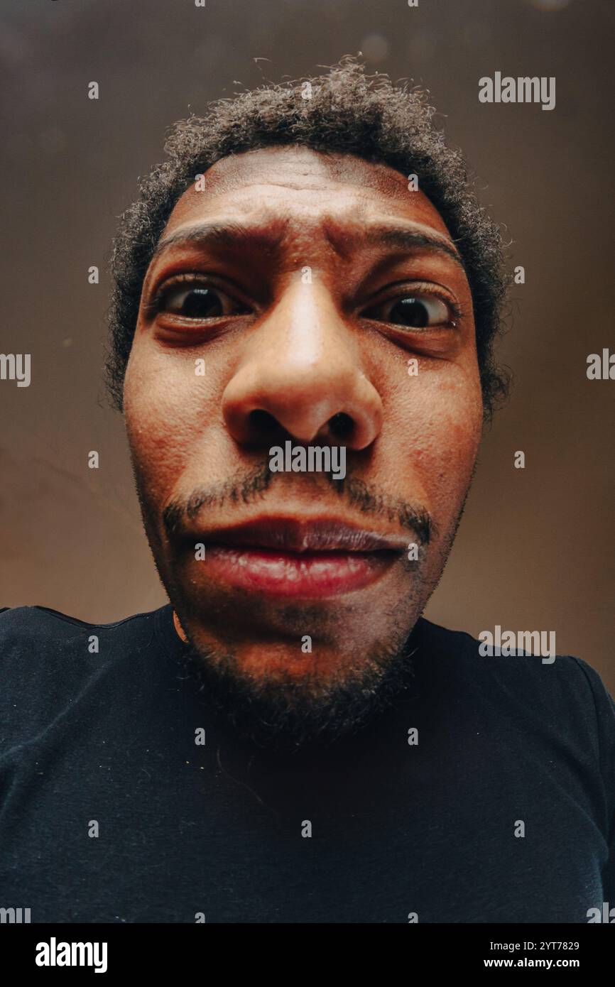 Close-up portrait of a young man making a funny face, captured with a ...