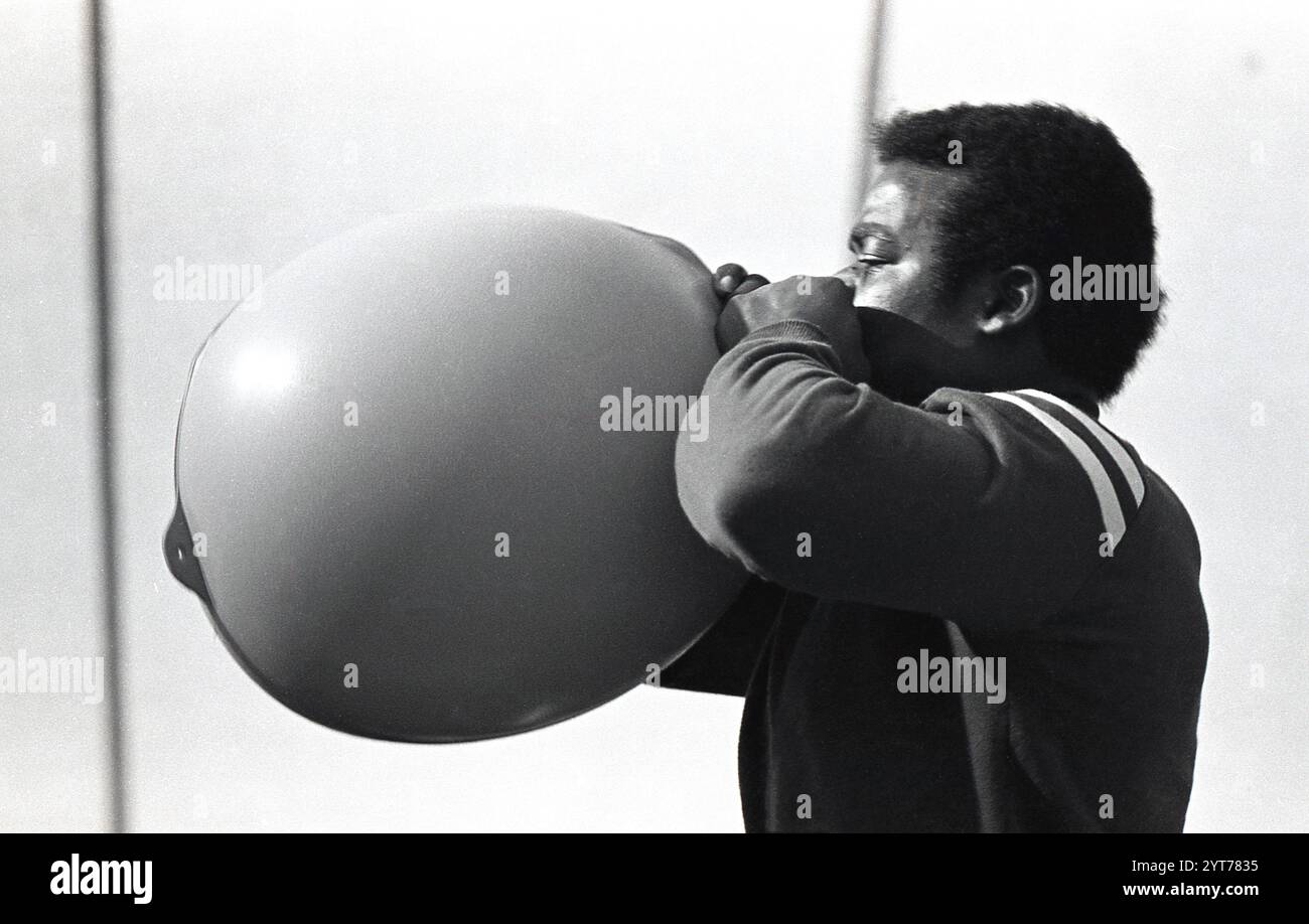 1968, historical, side-view of a man blowing up a rubber sphere, a ...