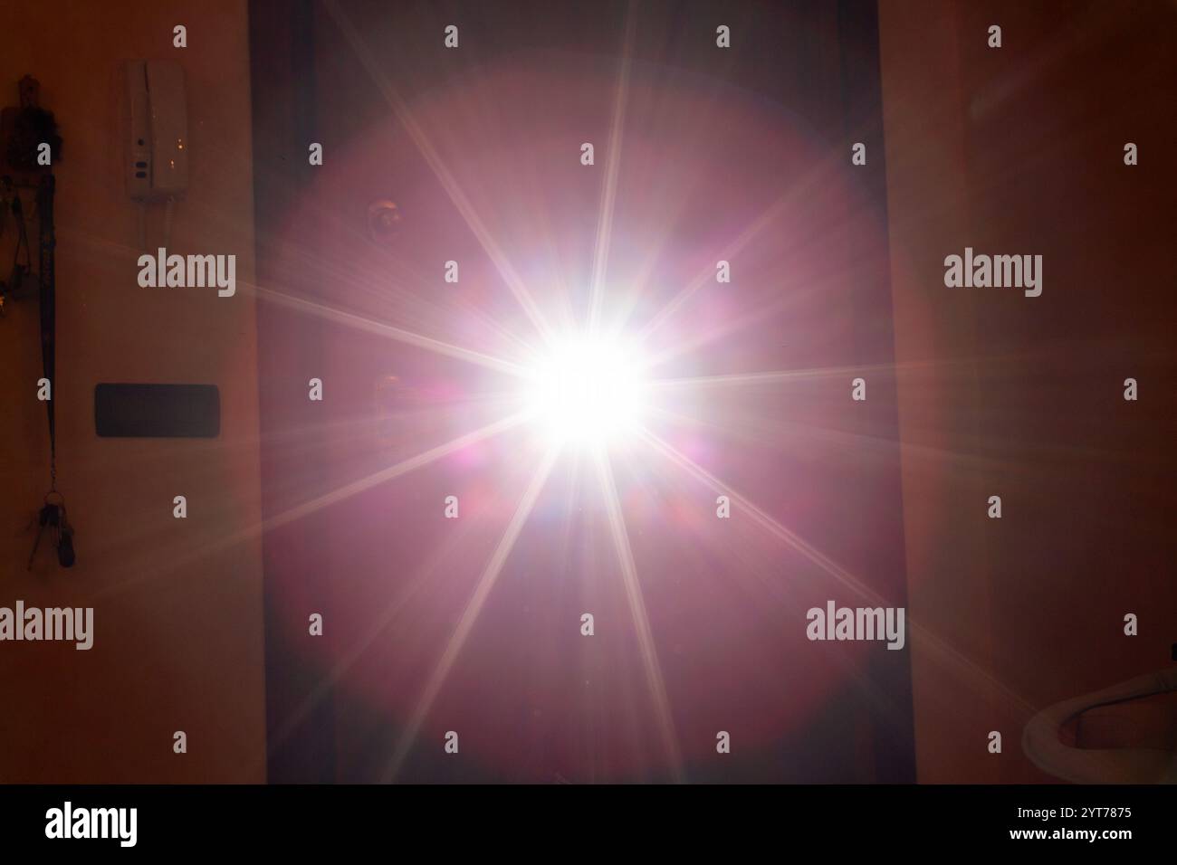 Lens flare effect created by bright light shining through door in dark ...