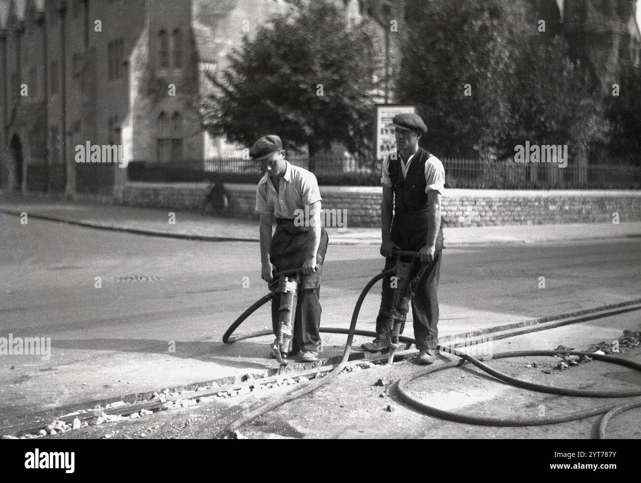 circa 1930s, historical, two road workers wearing flat caps, laying ...