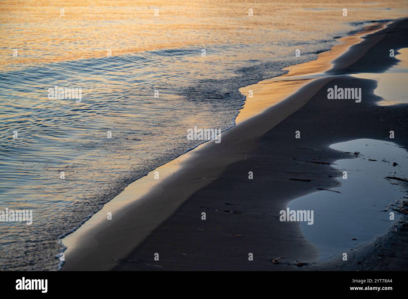 Surface of water, reflection of sunrise light, wave and puddle on beach ...
