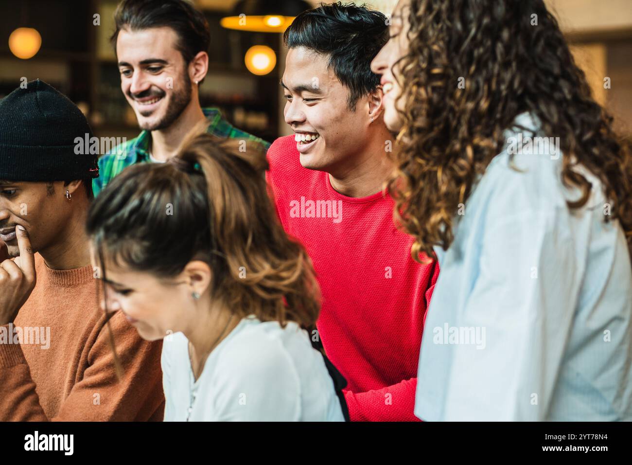 Cheerful university students are collaborating on a project, enjoying their time together and ...