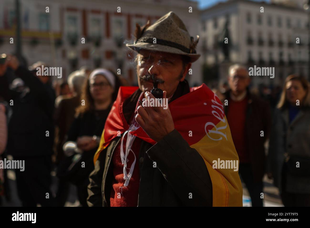 Madrid, Spain. 06th Dec, 2024. A man wrapped in a Spanish flag smokes ...
