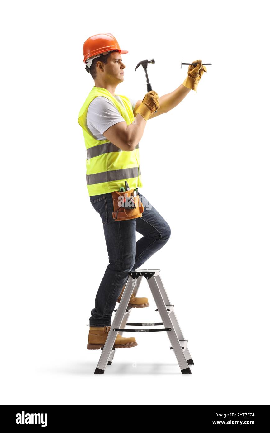 Construction worker hammering a nail on a wall isolated on white ...
