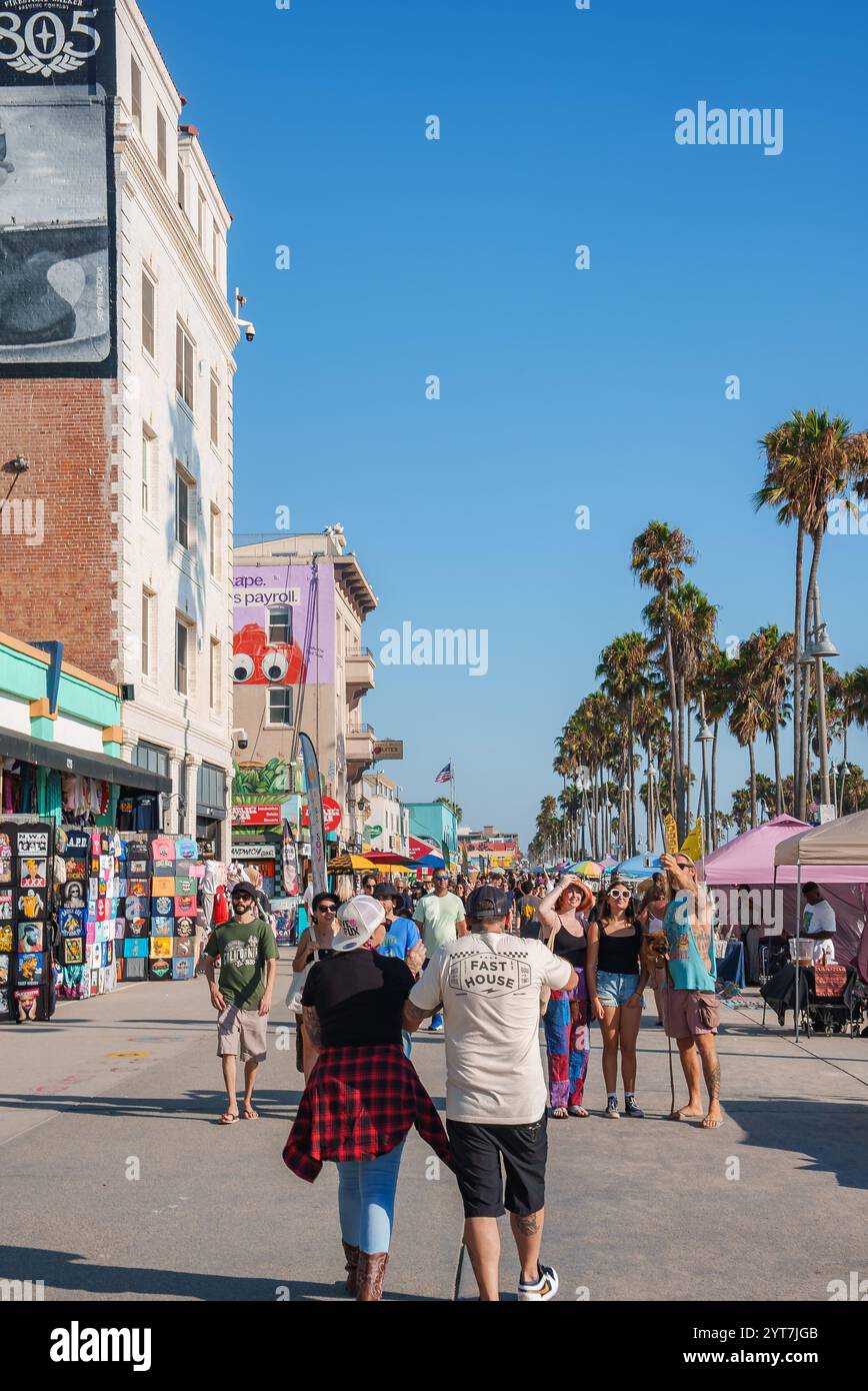 Venice Beach boardwalk is bustling with people, palm trees, and ...