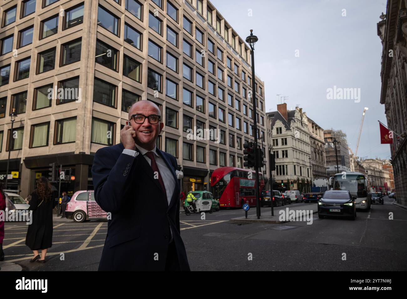A London businessman speaks on his smartphone whilst crossing the ...