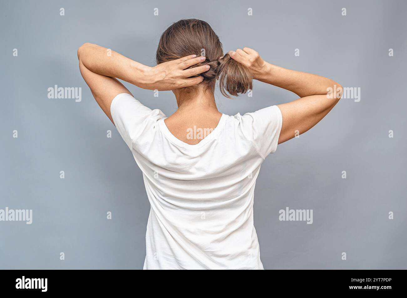 Woman collects long disheveled hair in a ponytail. Damaged hair. Beauty ...