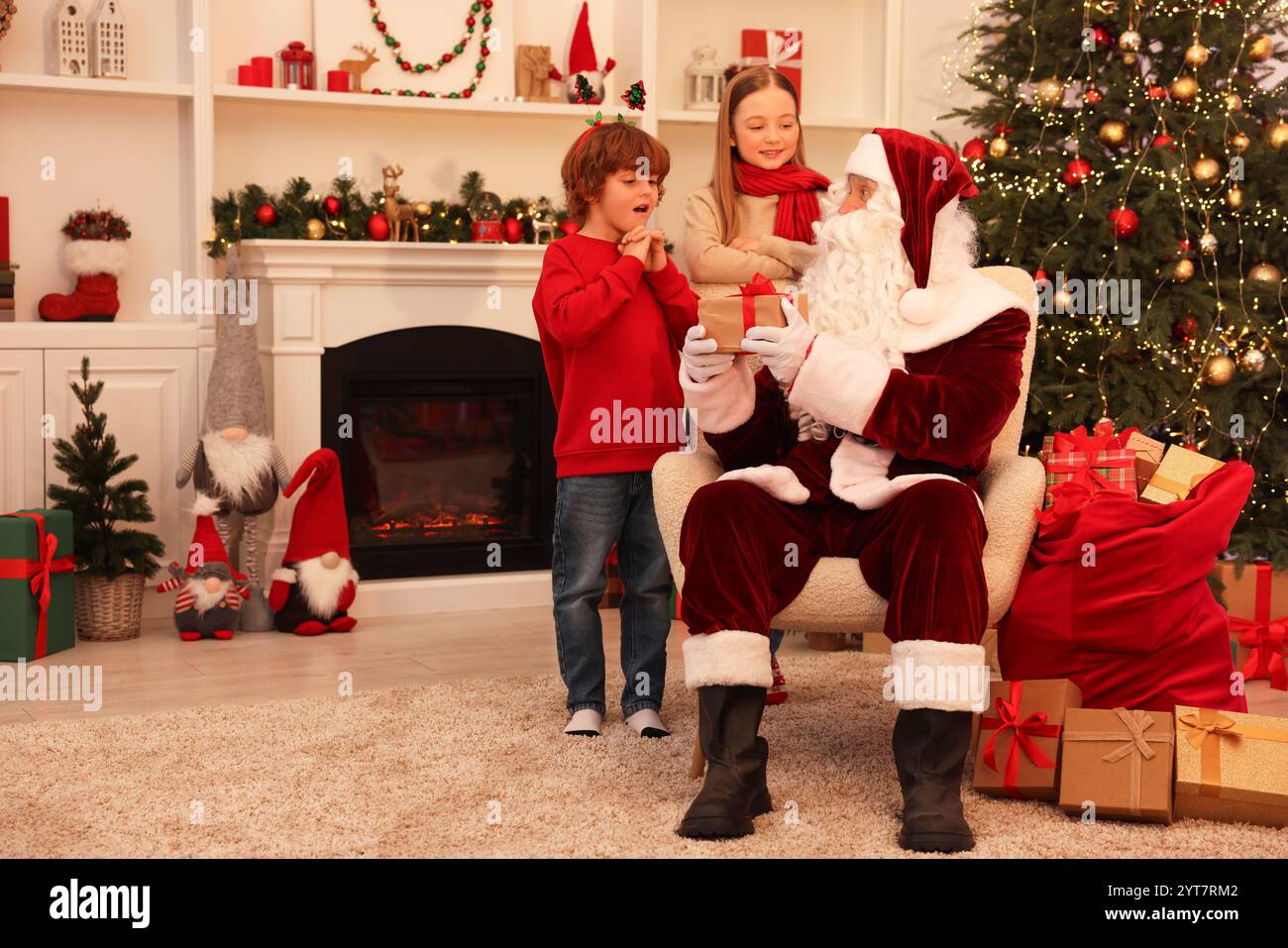 Christmas celebration. Santa Claus giving gift box to kids at home ...