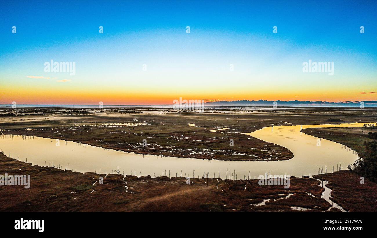 A river winding through the marsh as the sunrises over the horizon ...