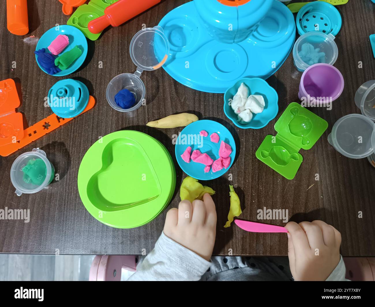 The child molds soft plasticine, plays at the table with a set of molds ...