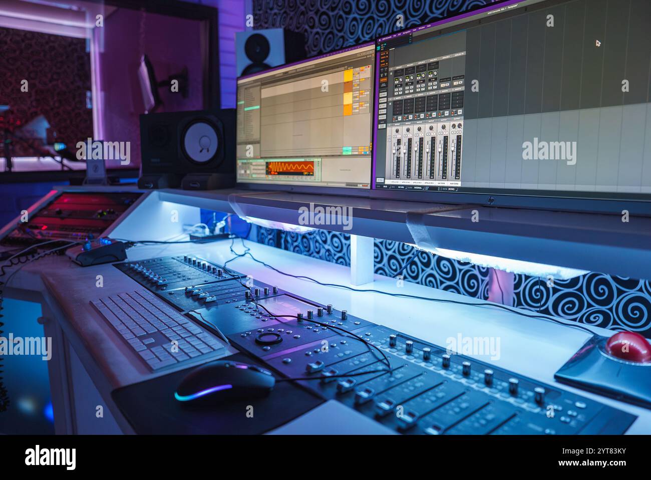 A sleek music studio features large monitors, a mixing console ...