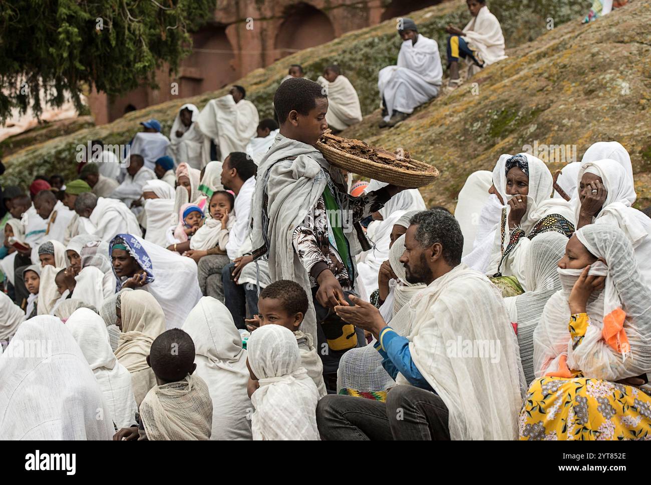 Altar boy distributes blessed bread to worshippers in traditional white ...