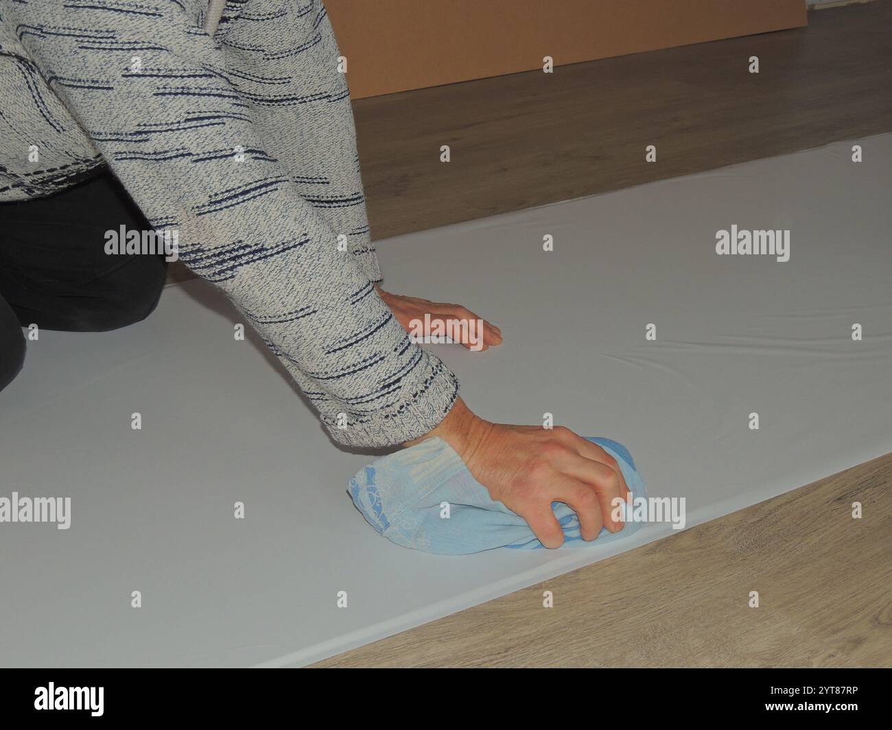 a man kneeling smooths out with a cloth the unevenness on the white ...