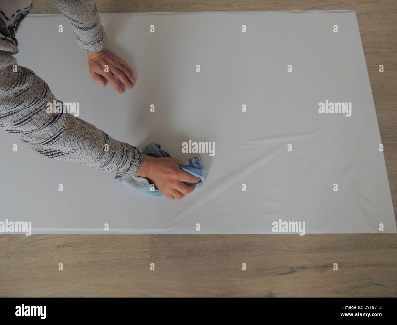 hands of a man with a piece of cloth with which he smooths out sticky ...