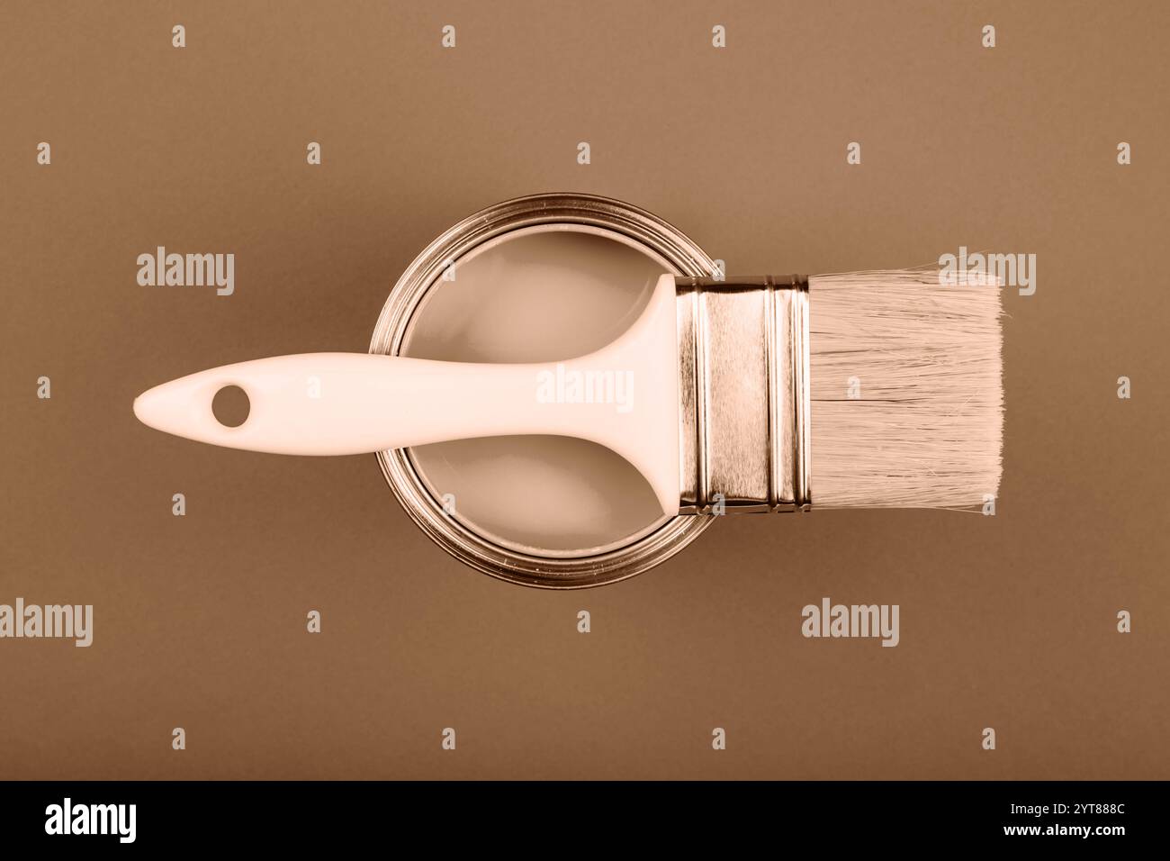Paintbrush resting on open paint can in a neutral shade background ...