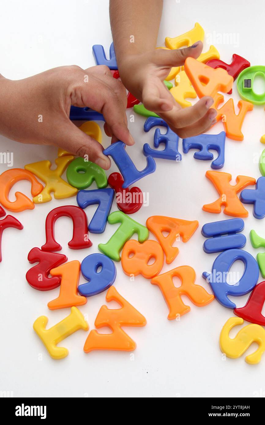 Brown hands of mom and daughter play with the game of colored letters ...